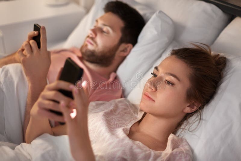 Couple Using Smartphones in Bed at Night Stock Photo - Image of laying ...