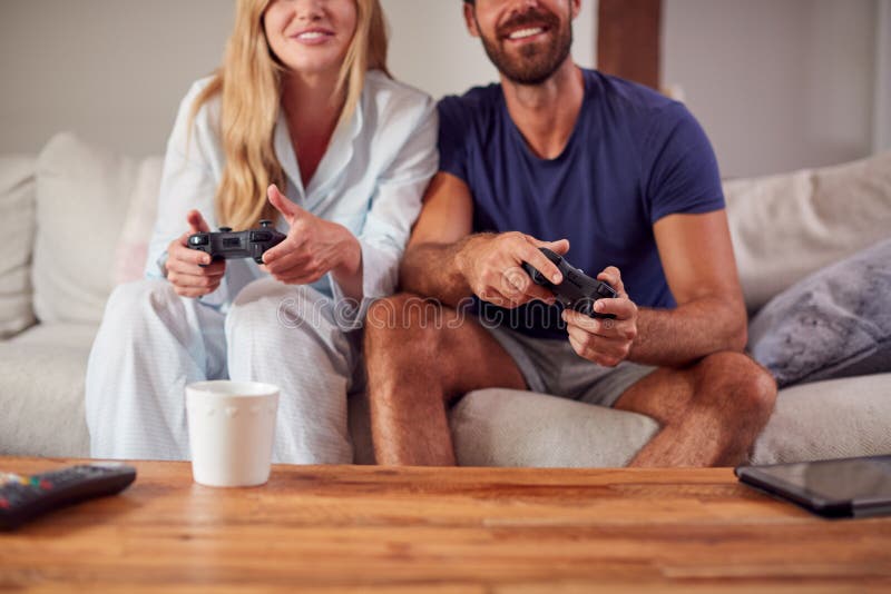 Couple Wearing Pyjamas Sitting on Sofa Playing Computer Game Together ...