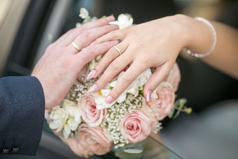 Couples Hands Wearing Their Wedding Rings Resting on the Wedding Bouqet ...