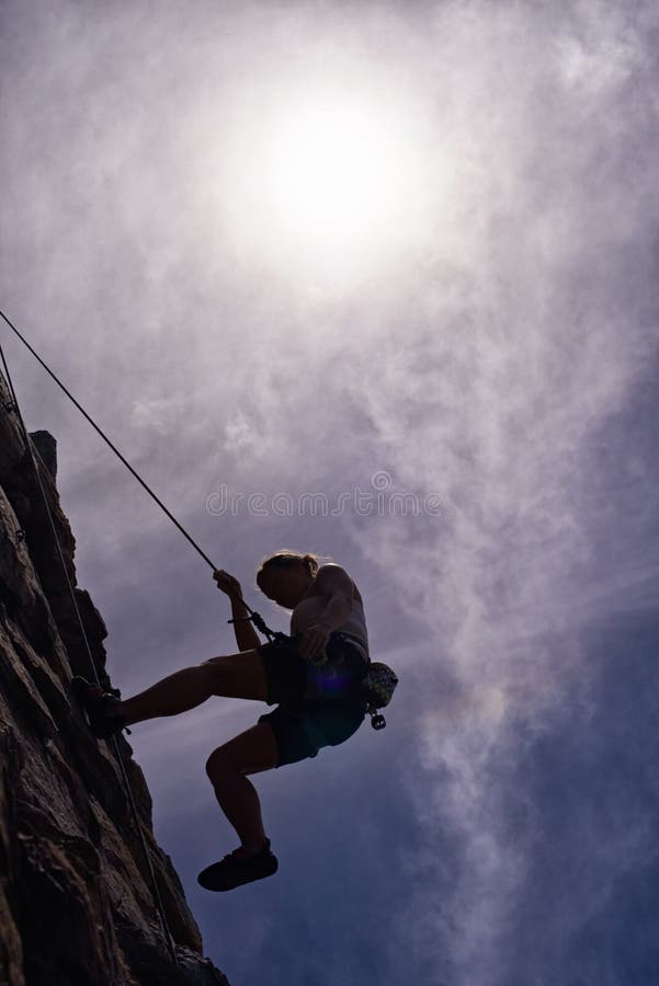 The Courage of a Rock Climber. a Silhouette of a Young Woman Abseiling ...