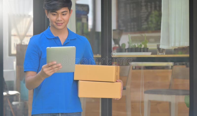 The Courier Holding a Package Box is Using a Tablet To Verify the ...