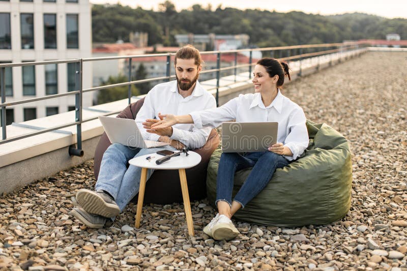 Coworkers Collaborating on Rooftop Workspace with Laptops Stock Photo ...