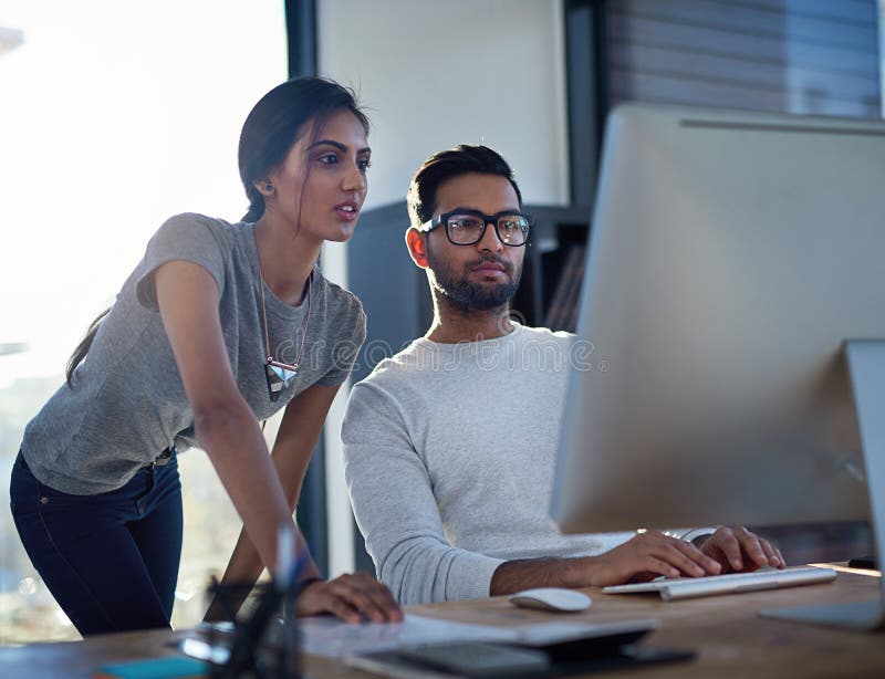 Coworkers in Synch. Two Young Coworkers Using a Computer Together at ...