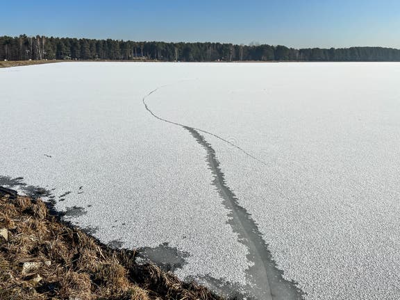 A Crack in the Ice Sheet on a Pond Lightly Covered with Snow Stock ...