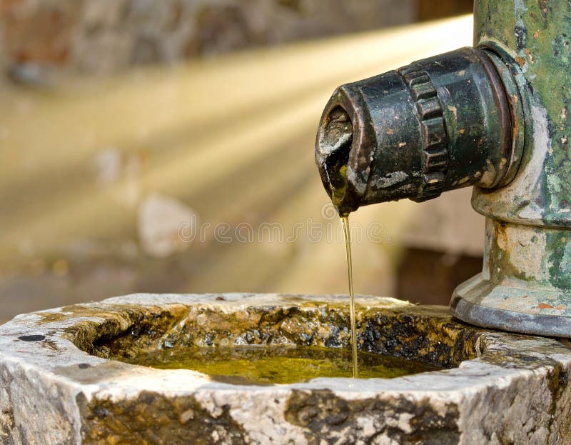 A Cracked Olive Press Dripping Oil Onto a Stone Slab with Rays of Light ...