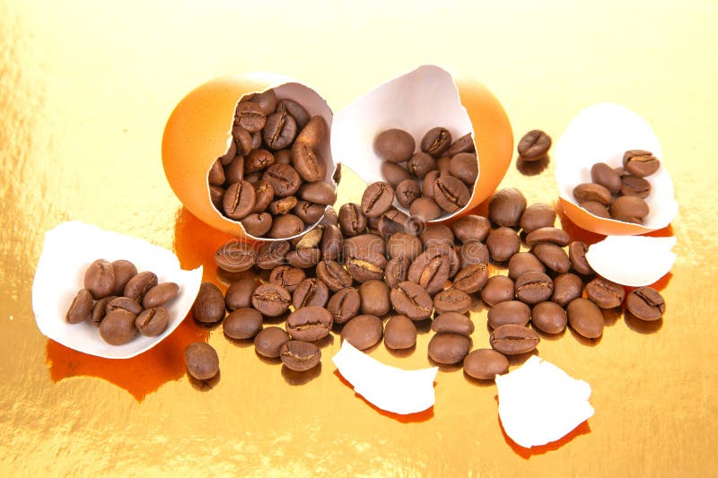 A Cracked Orange Egg Spills Coffee Beans Onto a Reflective Gold Surface ...