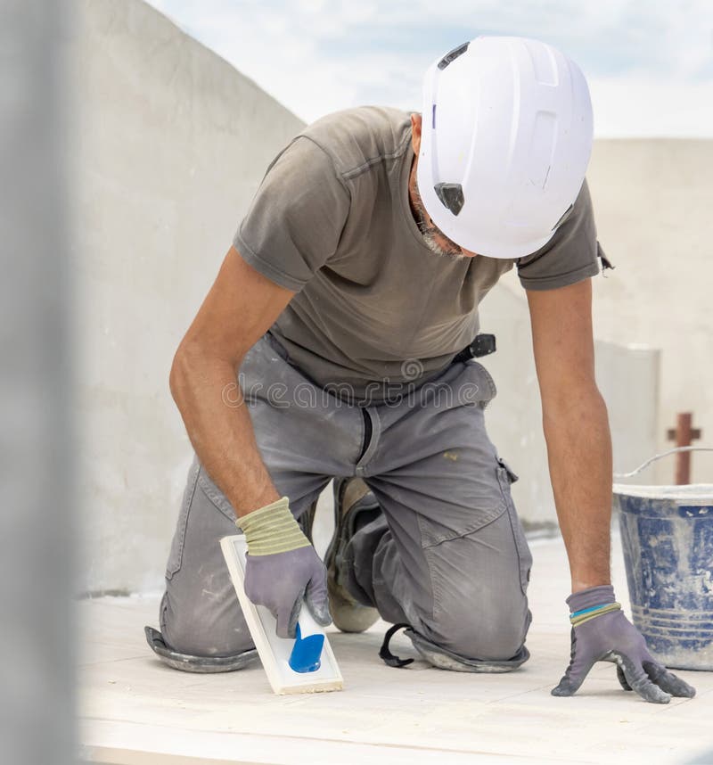 Craftsman in Grey Work Clothes Puts Grout with a Float Sitting on His ...
