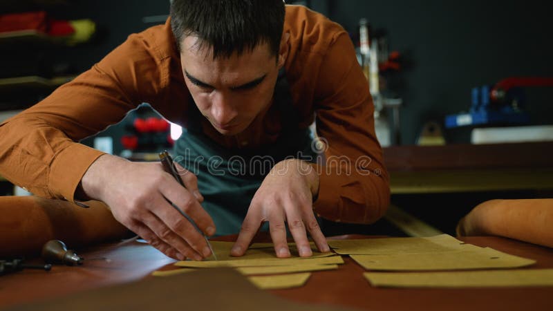Craftsman Intently Tracing Patterns Onto Leather Sheets, Showcasing ...