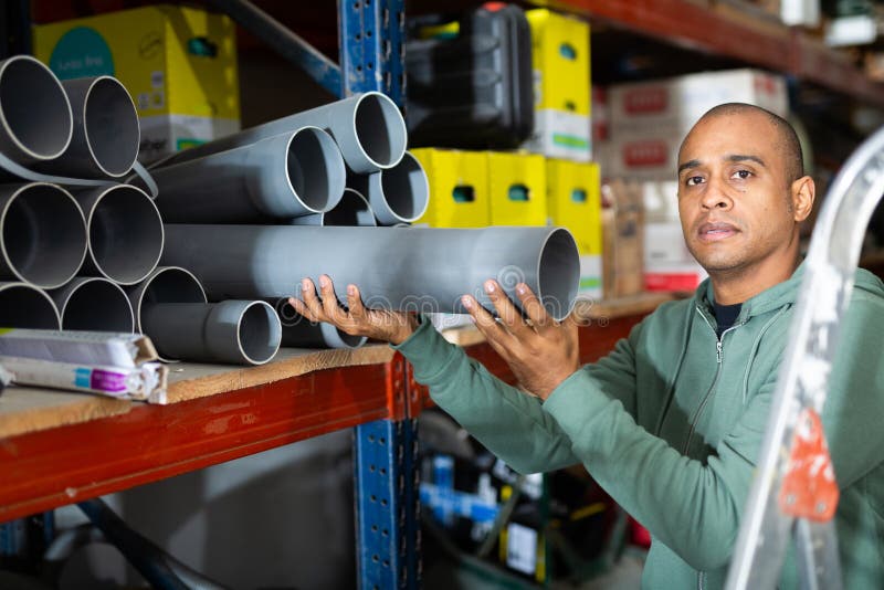 Salesman in Overalls with Plumbing Fittings at Hardware Store Warehouse ...