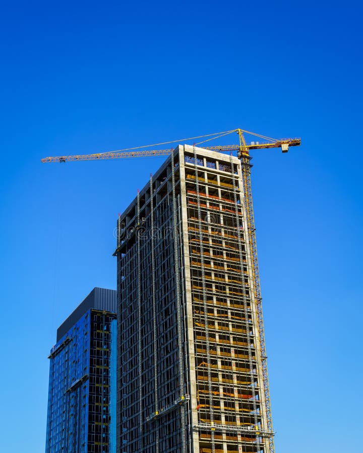 A Crane Building a Modern Skyscraper Against a Blue Sky. Construction ...