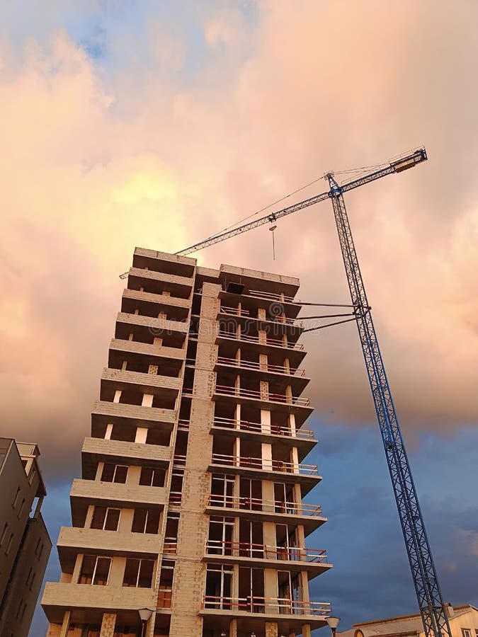 A Crane is Building a Tall Building Against a Dramatic Sky with Clouds ...