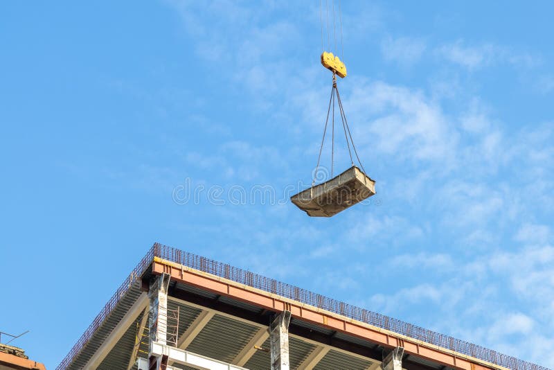 A Crane at a Construction Site Lifts a Container with Concrete Mortar ...