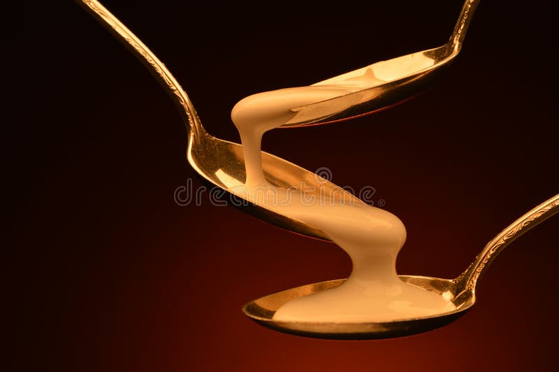 Cream Pouring from One Spoon into Another Stock Photo - Image of ...