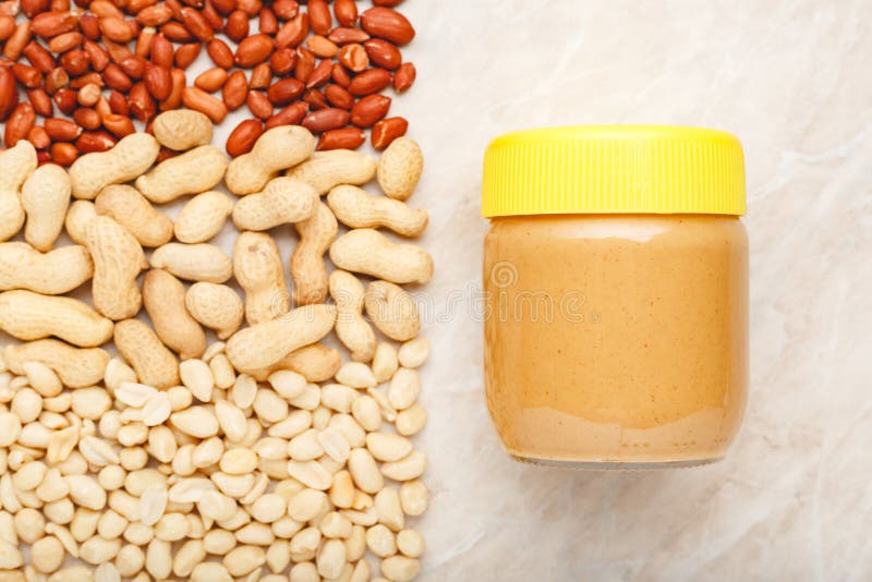 Creamy Peanut Paste in Glass Jar with Yellow Cap and Peanuts in the ...
