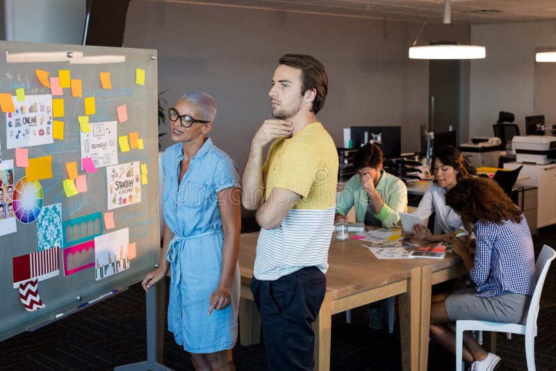 Creative Business People Reading Sticky Notes on Glass Wall with Stock ...