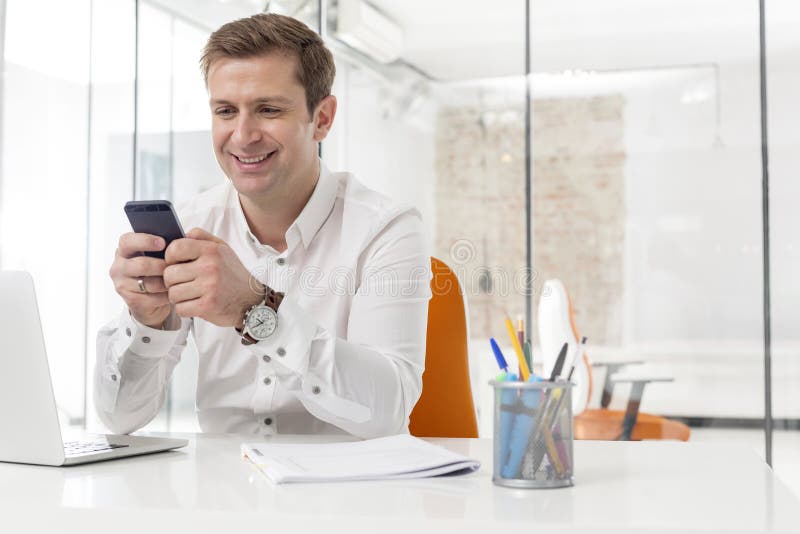 Businessman Smiling while Using Smartphone in Office Stock Image ...