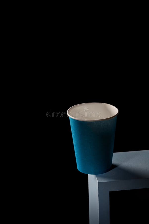 A Blue Paper Cup Stands on the Edge of a Blue Square Frame on a Black ...