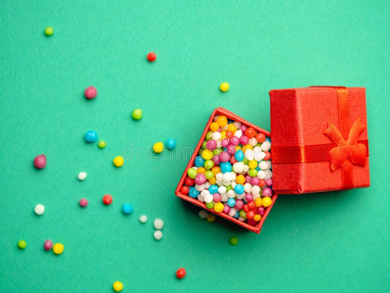 Creative Layout of Gift Box Filled with Colorful Candies Over Green ...