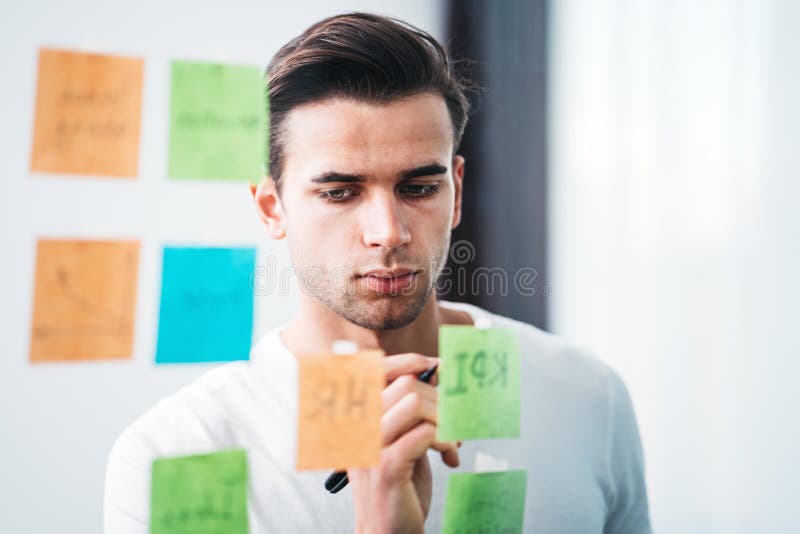 Creative Man Writing Sticky Note on Glass Wall at Office Space Stock ...