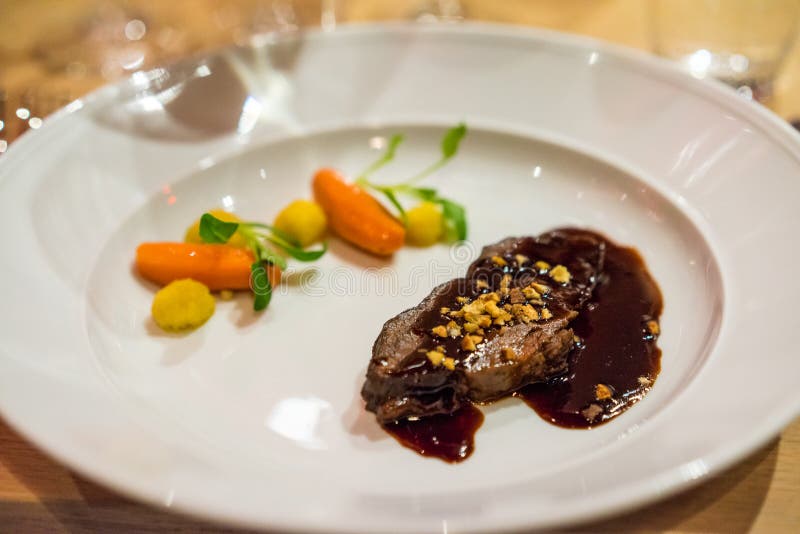 A Plate with Veal Meat on Greens with Vegetables and Olives Under Nut ...