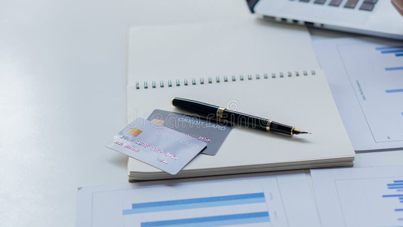 Credit Card Placed on a Notebook and a Graphed Pen with a Laptop on the ...