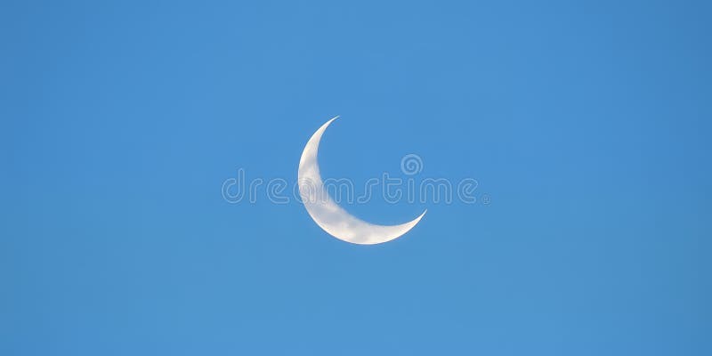 A Crescent Moon with Cloud Texture Against a Bright Blue Sky during the ...