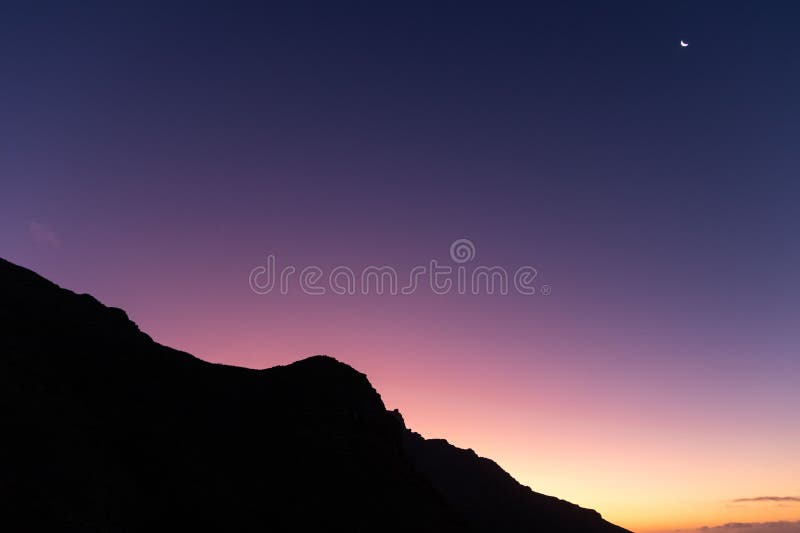 Crescent Moon Setting Over a Mountainous Landscape at Sunset Stock ...