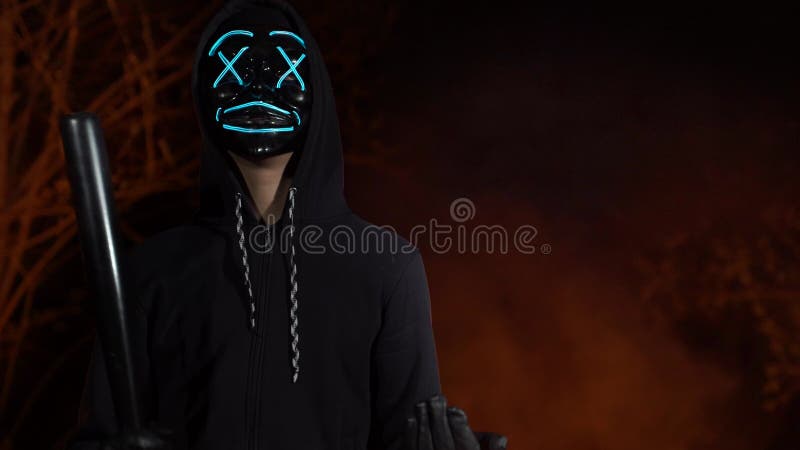 Criminal in Mask Holding a Baseball Bat on the Background of a Burning ...