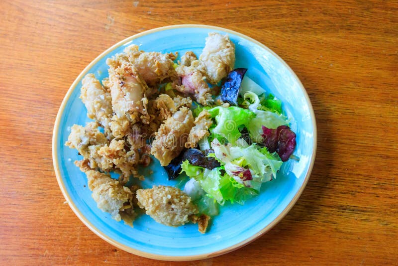 Crispy Deep Fried Baby Octopus Served with Salad on Wooden Table. Top ...