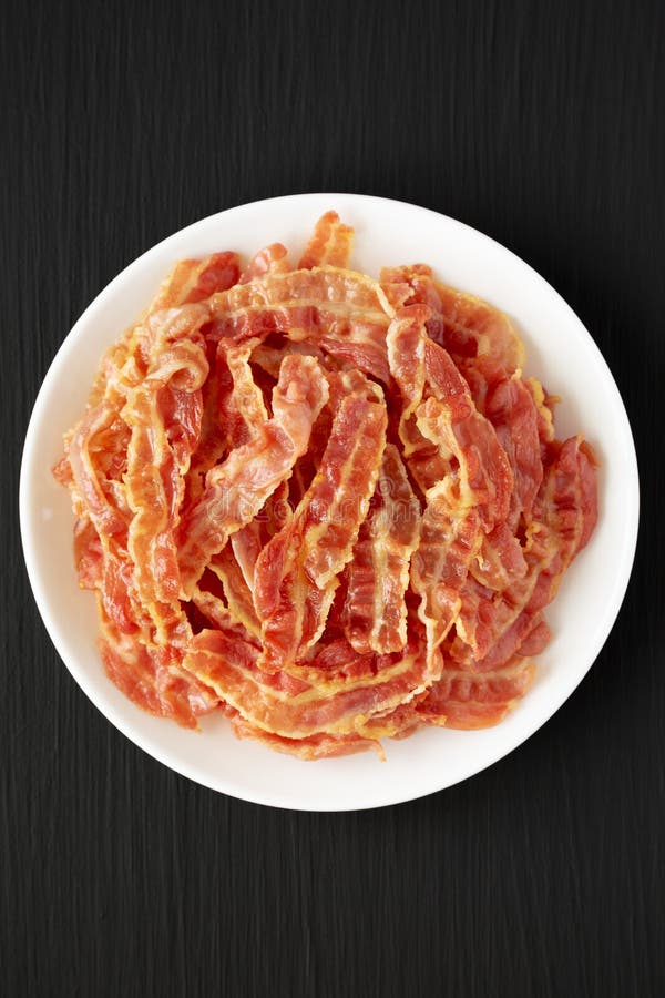 Crispy Fried Bacon on a White Plate on a Black Surface, Top View. Flat ...