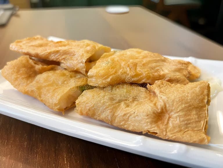 Crispy, Golden-brown Fried Bean Curd Rolls, Possibly Filled, Served on a White Rectangular Plate ...