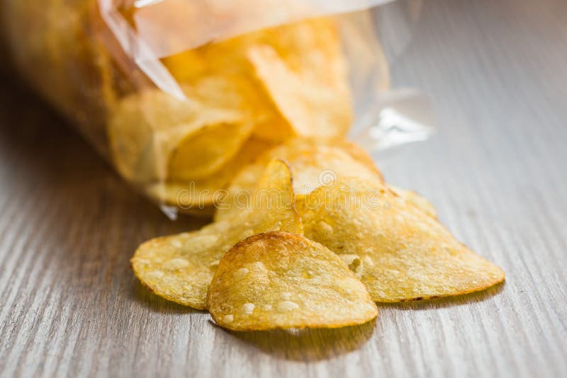 Crispy Potato Chips Spilled from Plastic Bag on a Wooden Table Stock ...
