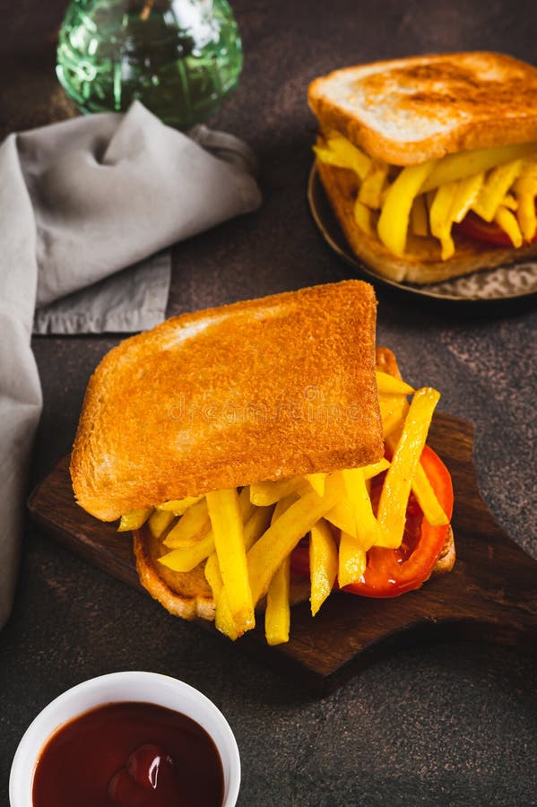 Crispy Sandwich with French Fries and Tomato on a Board on a Table ...