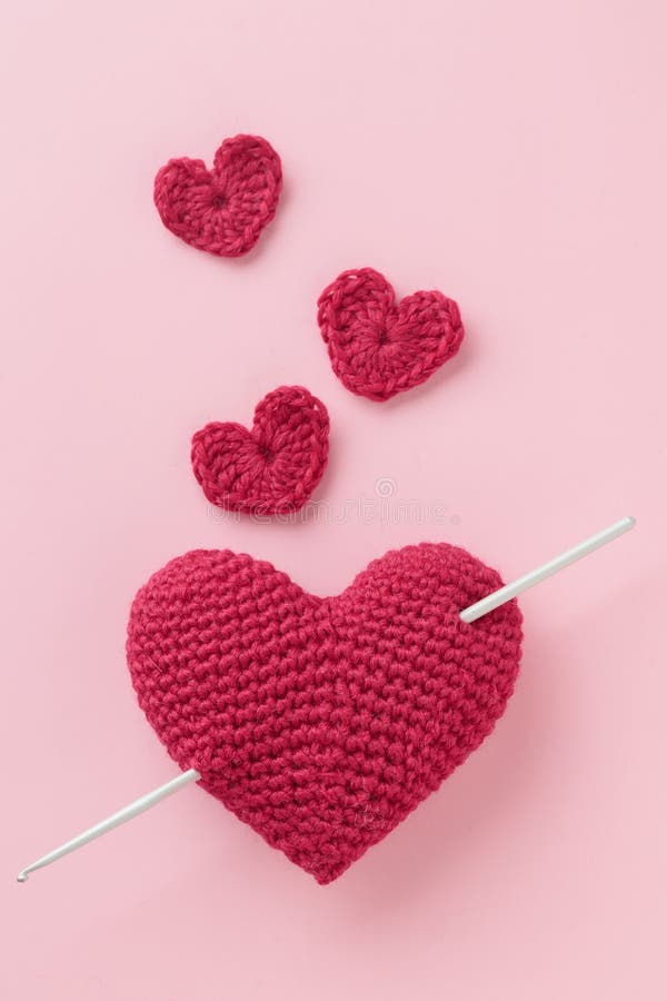 Crocheted Amigurumi Pink Heart With Crochet Hook And Skein Of Yarn On A
