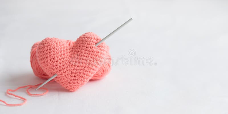 Crocheted Amigurumi Pink Heart With Crochet Hook And Skein Of Yarn On A