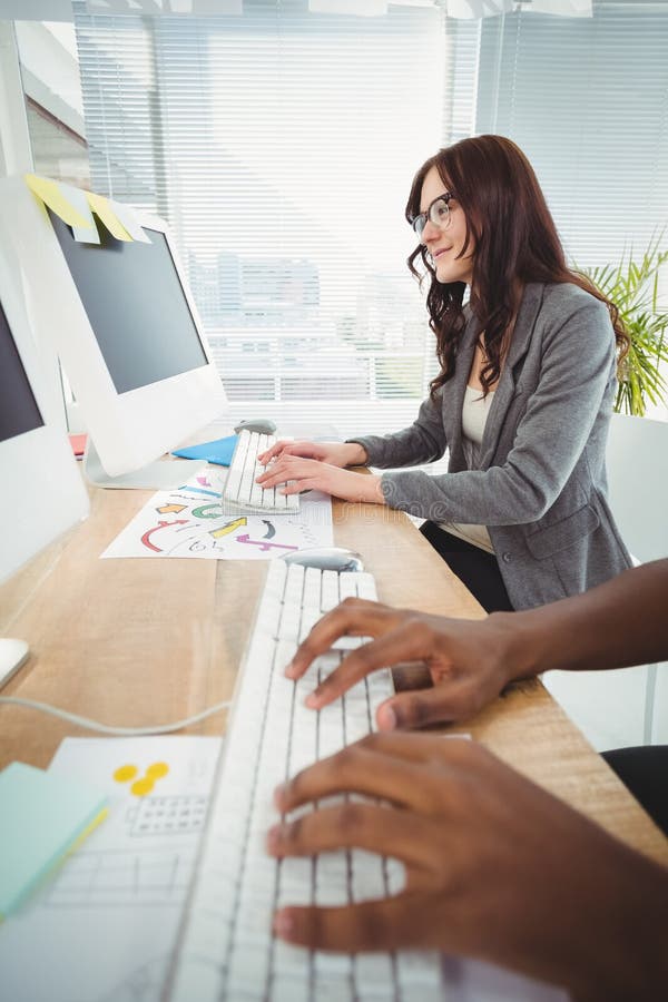 Cropped Hands Typing on Keyboard at Computer Desk with Businesswoman ...