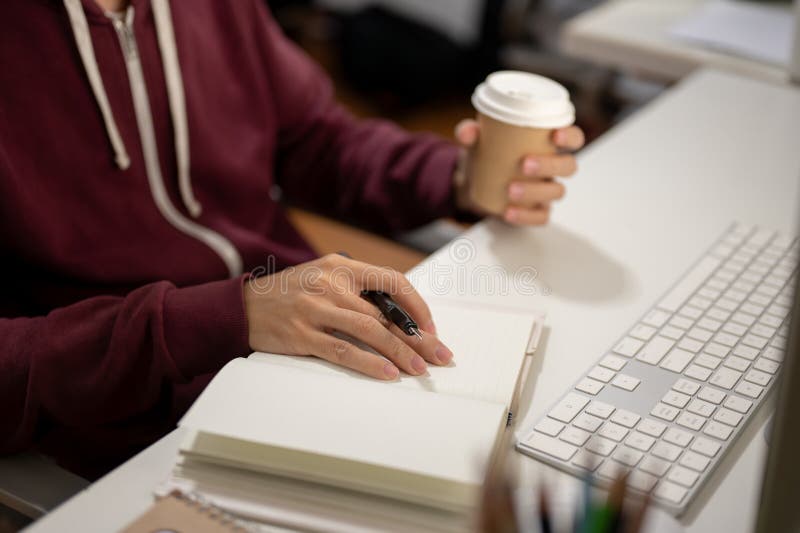 Cropped Image of a Man Sitting in Front of a Computer, Taking Notes in ...