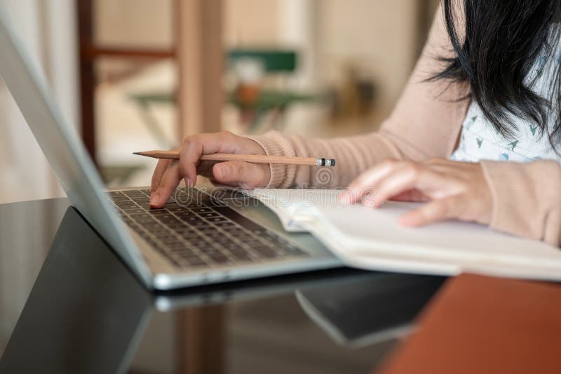 A Cropped Image of a Woman Working on Her Laptop, Taking Notes in a ...