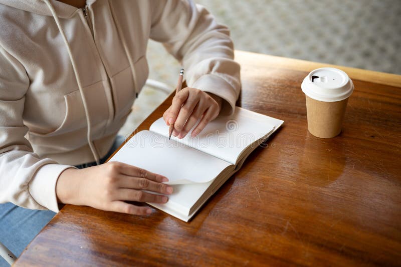 Cropped Image of a Woman Writing Something in a Book at a Table in a ...