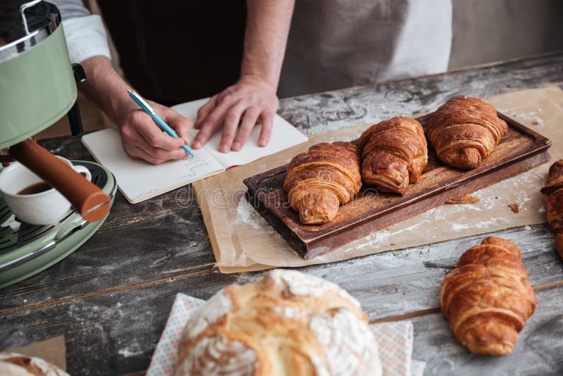 Old Baker Writing Down Old-time Recipe in Bakery Notebook Surrounded by ...