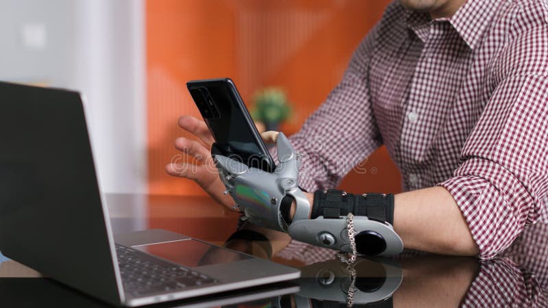 Cropped Shot of Man with Bionic Arm Using Smartphone Sitting at Desk in ...