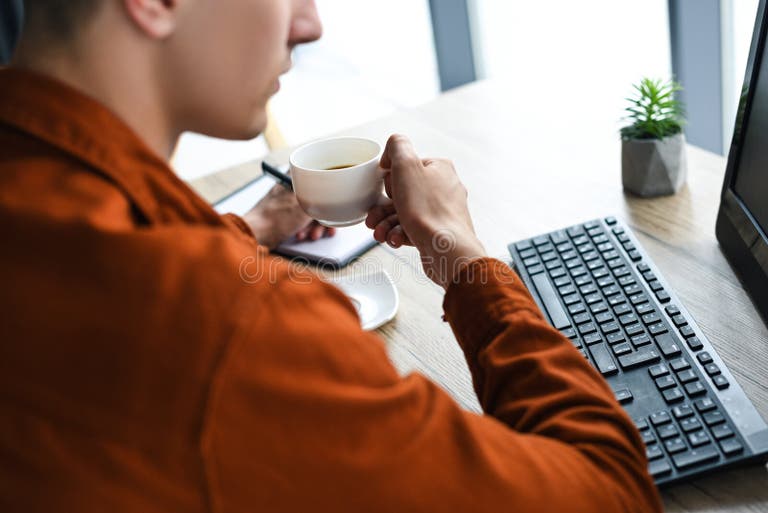 Cropped Shot of Man Drinking Coffee and Writing in Textbook at Table ...
