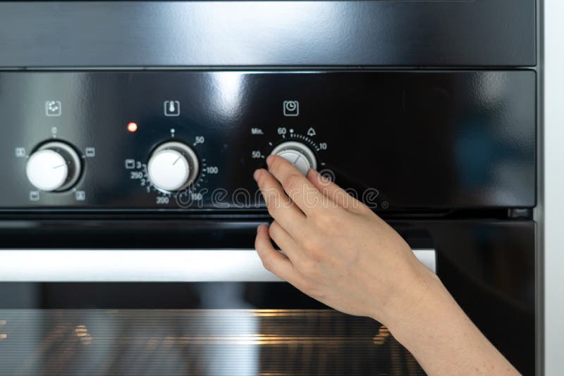 Woman Hand Turning Switch at Modern Built in Oven and Select Program ...