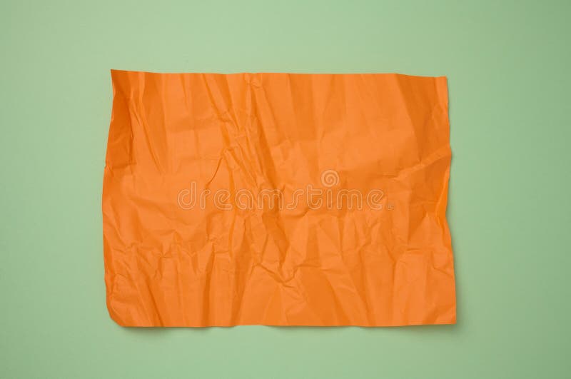 Crumpled Rectangular Sheet of Orange Paper on a Green Background, Top ...