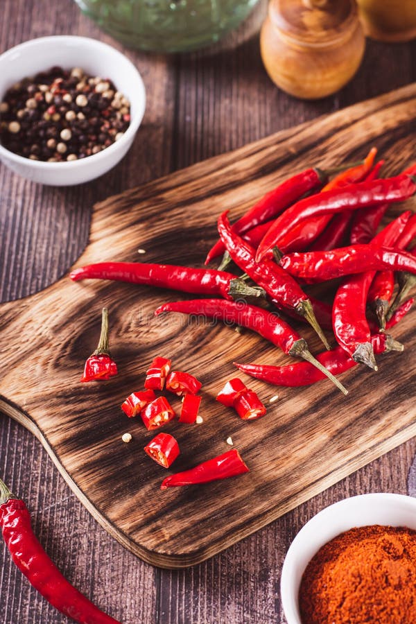 Crushed Red Hot Peppers and Whole Peppers on a Wooden Board Vertical ...