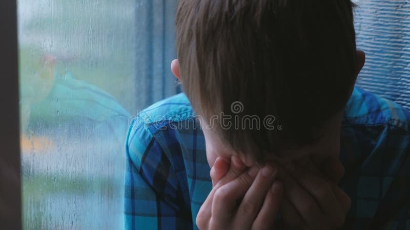 Crying Boy Looks Out the Window in the Rain. Stock Video - Video of ...