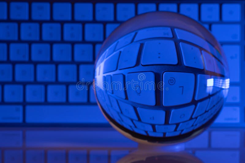 Crystal-clear Glass Ball Stands in Front of a White Computer Keyboard ...