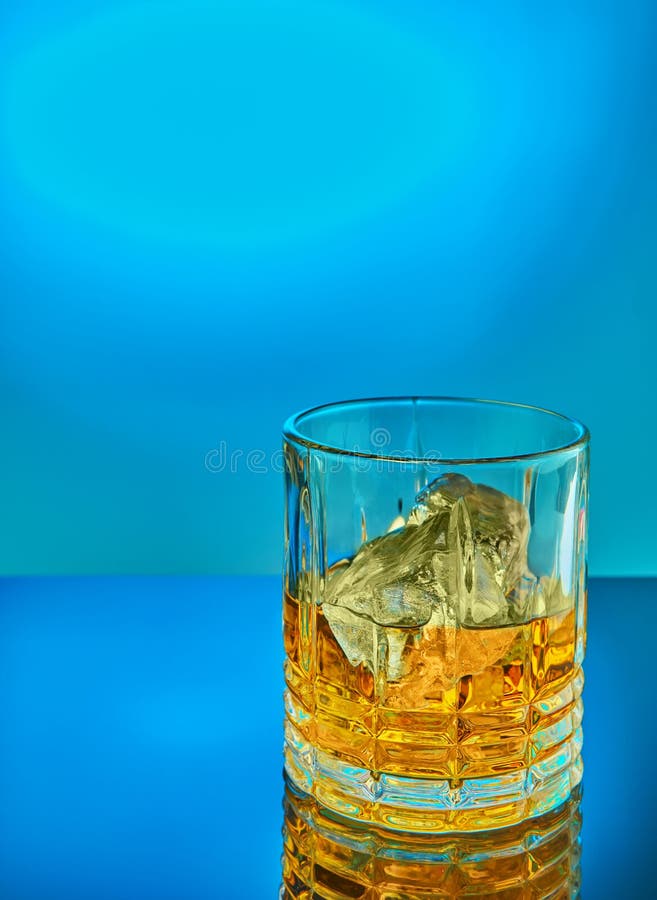 A Glass of Whiskey with Ice and Lemon on a Blue Background with Orange ...