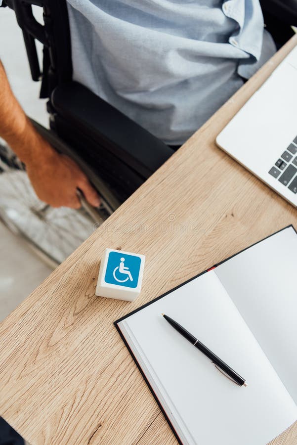 Cube with Disabled Sign and Man in Wheelchair Sitting at Table with ...