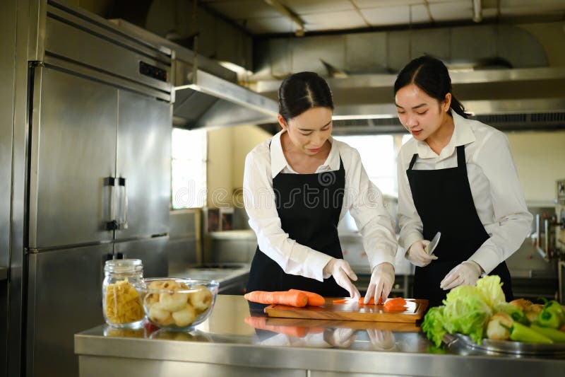 Culinary Instructor Guiding a Student through Carrot Slicing during a ...